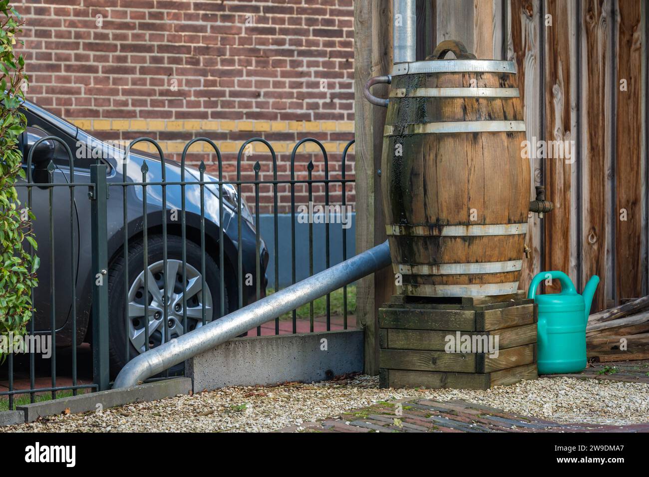 Rain barrel and watering can in front of a modern house, rainwater tank ...