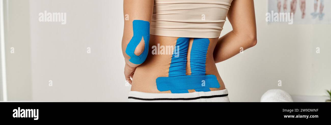 cropped view of young woman with kinesiological tapes on her back and ...