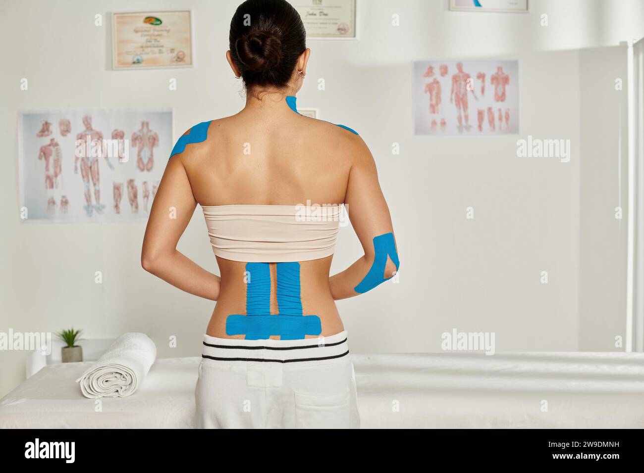 back view of young female patient with kinesio tapes on her back and ...