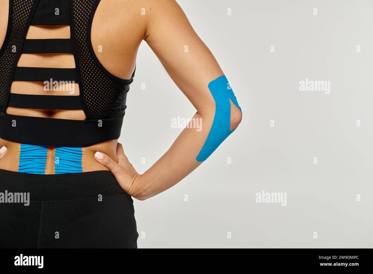 cropped view of young woman with arms akimbo in black sport wear with ...