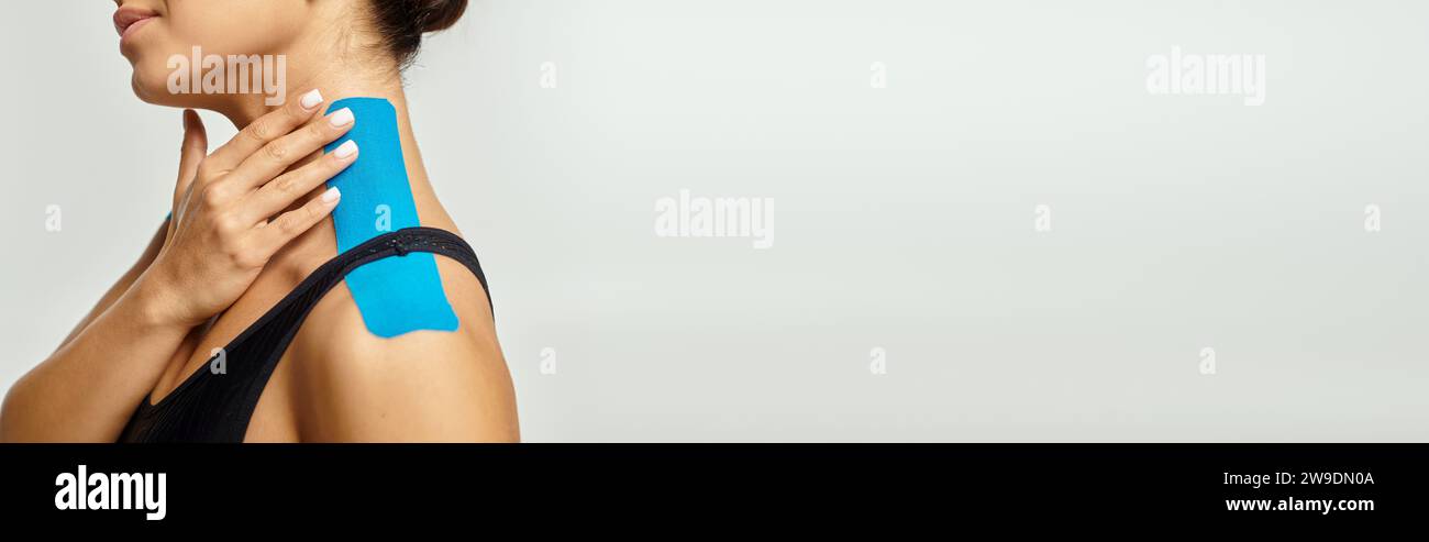 cropped view of woman posing in profile with kinesiological tapes on ...
