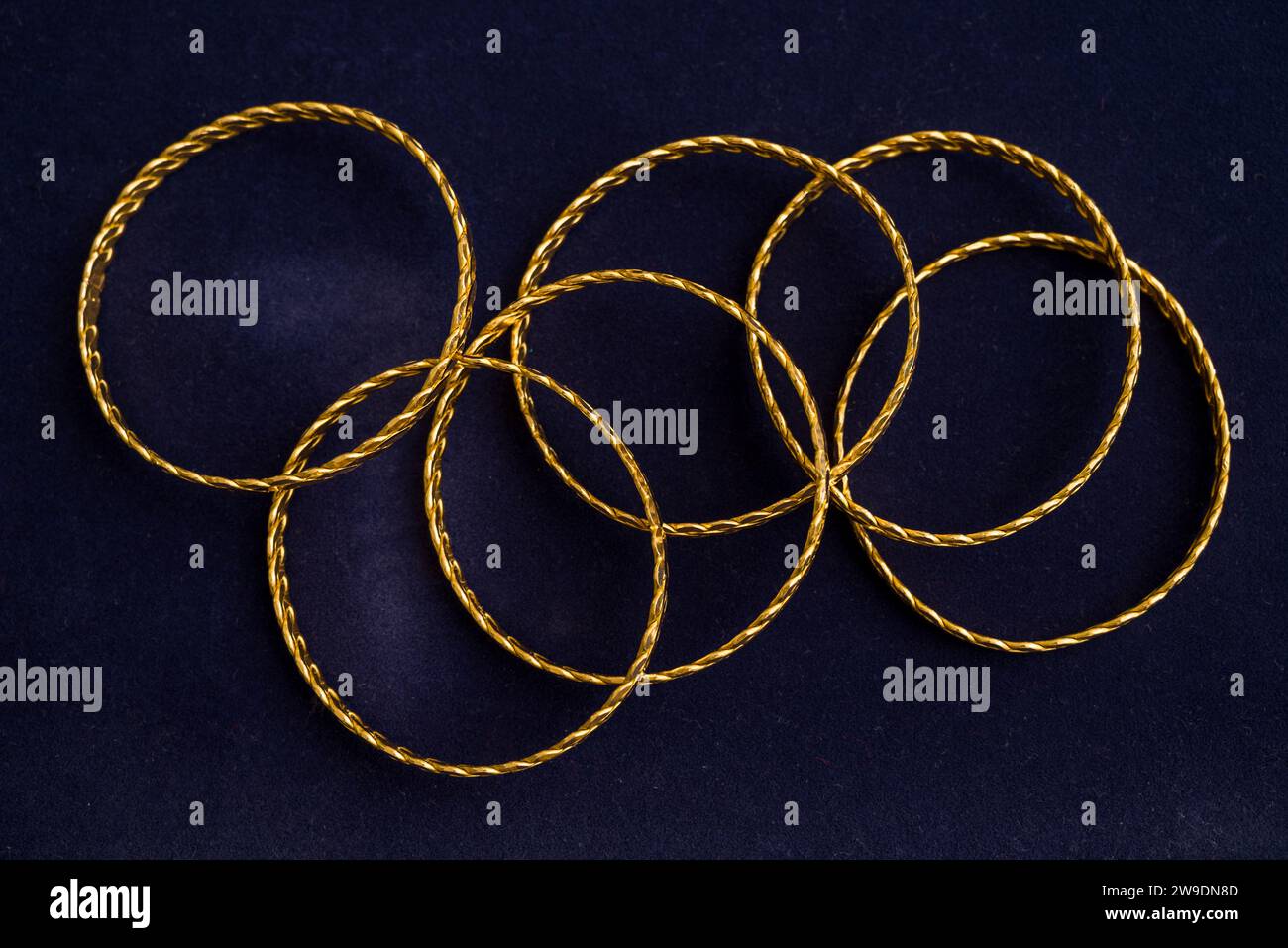 24k (24 carat) Turkish gold twist bracelet standing in a heap on a dark ...