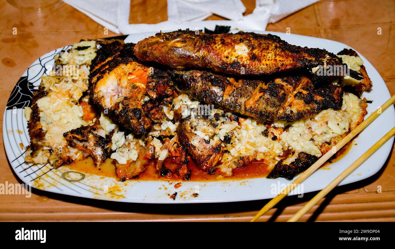 Delicious Asian fish fry served on a BBQ table. Grilled fish laid on ...