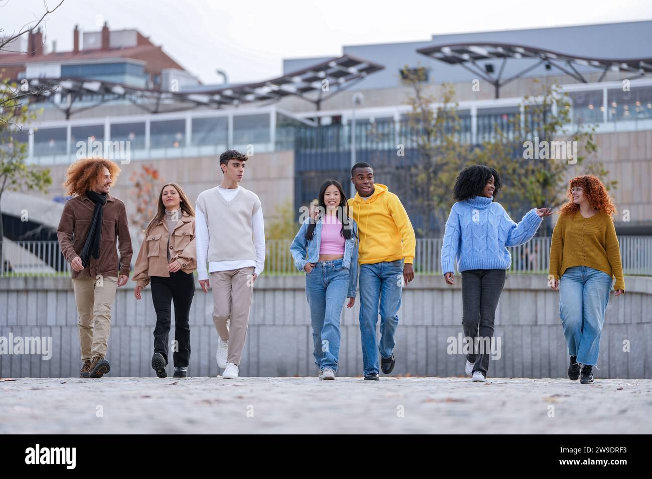 Group of six friends striding forward in an urban landscape, showing ...