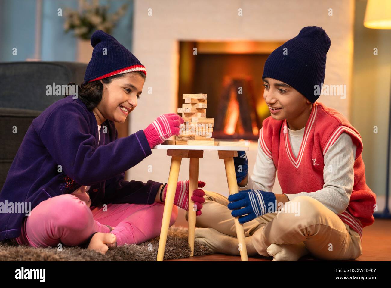 Indian siblings kids in winter wear busy playing block stacking game at ...