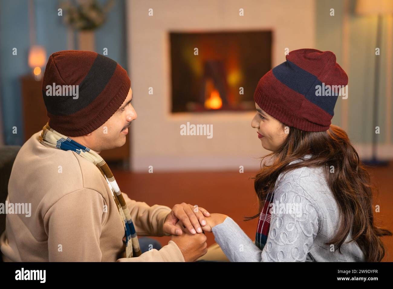 Happy Indian loving couples in winter wear talking together by holding ...