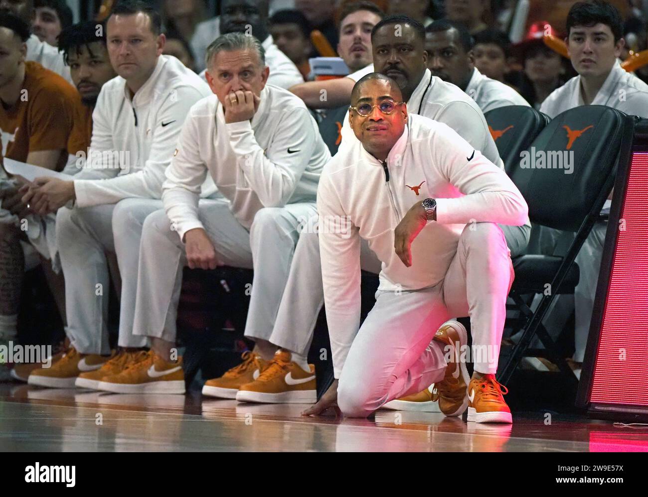 Texas head basketball coach Rodney Terry, kneeling, watches his team ...