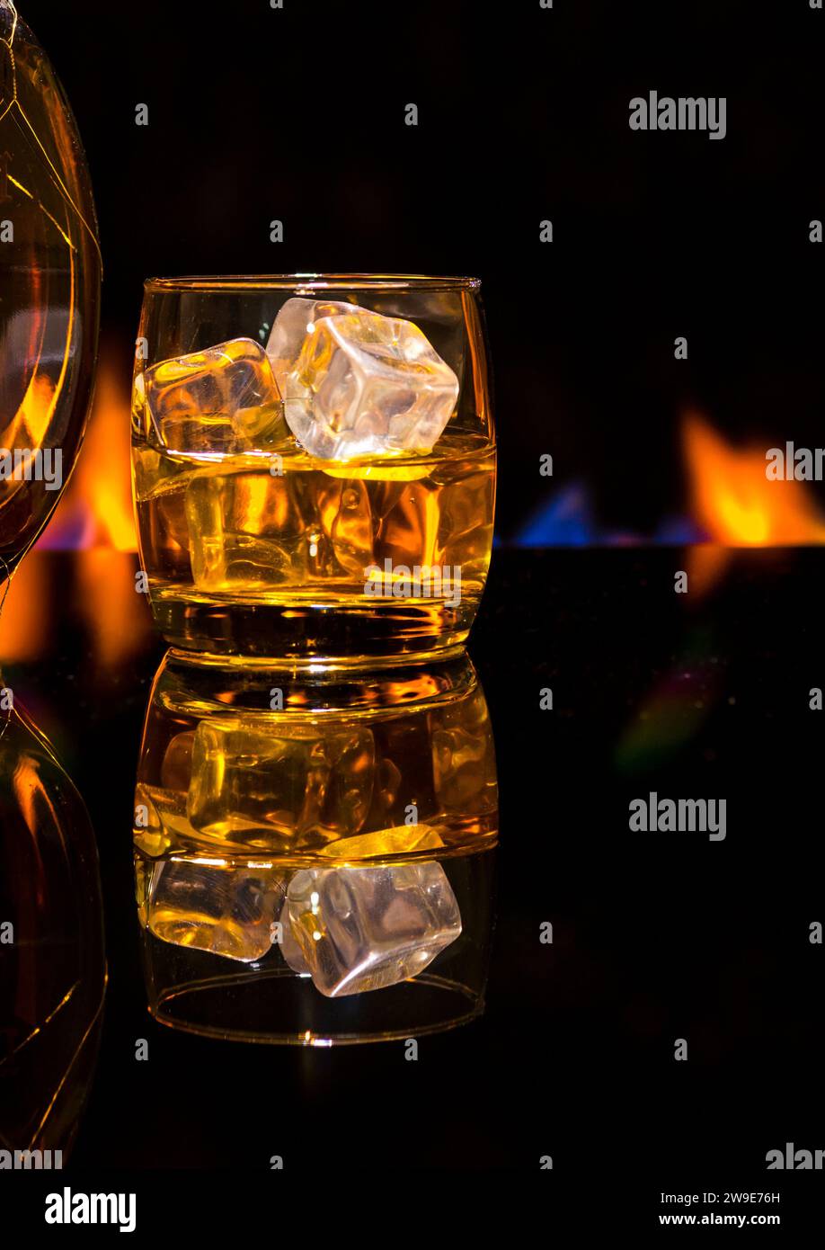 glass of whiskey on the rocks with ice cubes on black reflexive ...