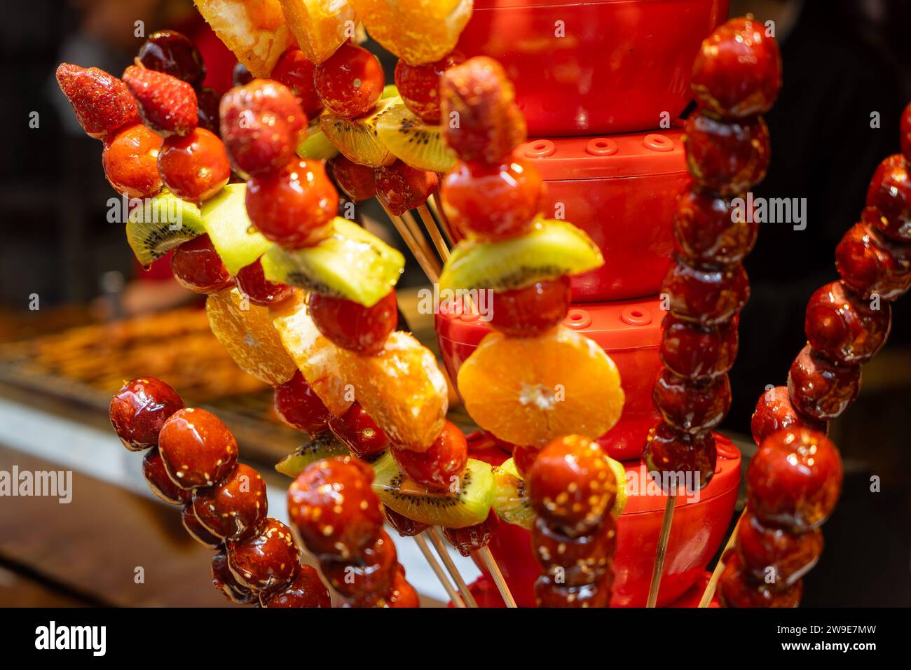 A vibrant display of fresh, smooth candied fruit skewers, a popular ...
