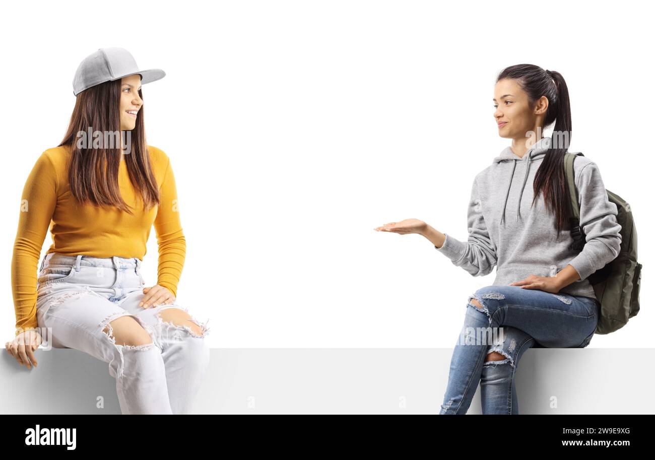 Female friends sitting on a blank panel and having a conversation ...