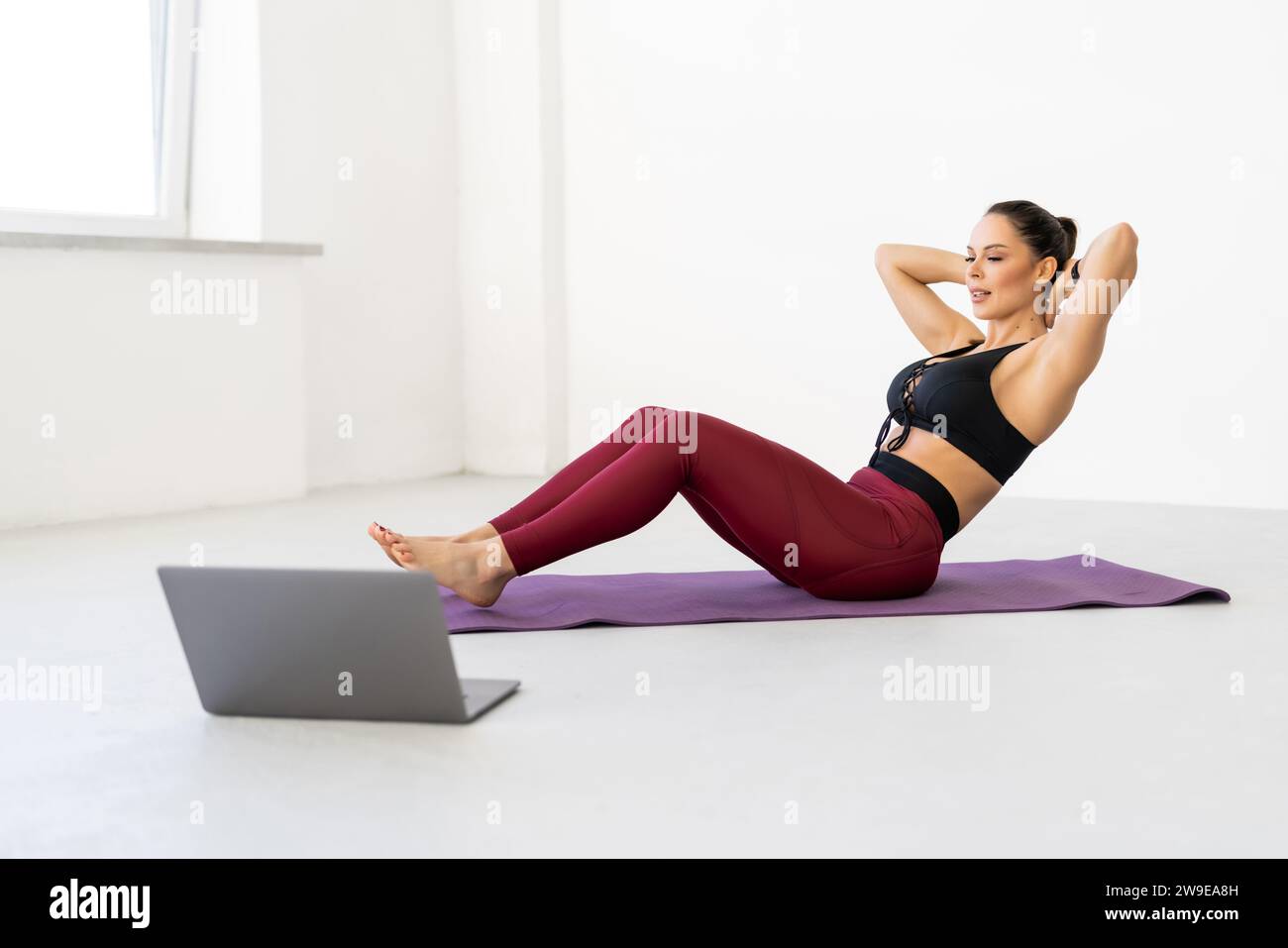 Positive young athlete exercising abs at home watching video workout ...