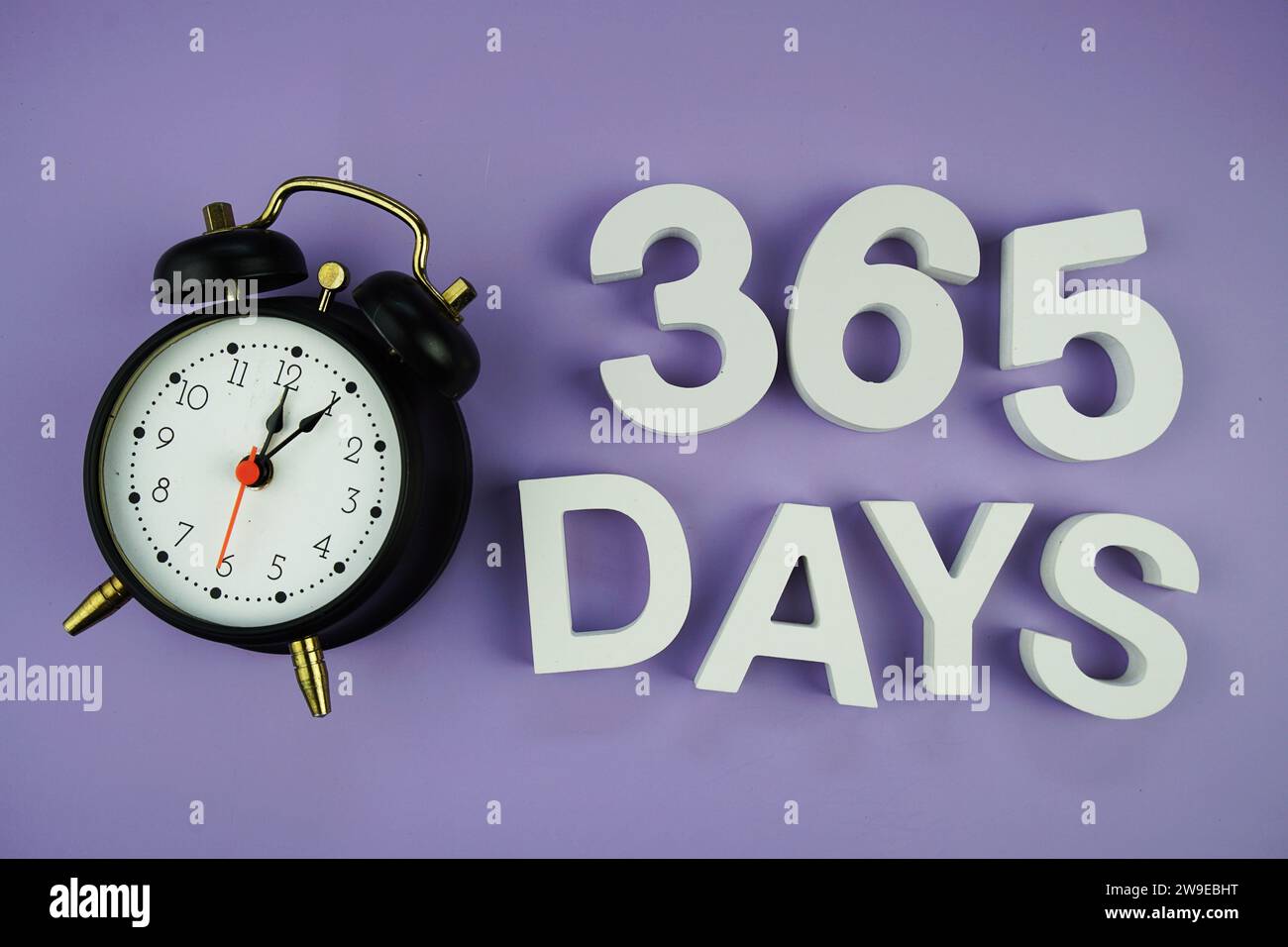 365 Days alphabet letters with alarm clock top view on purple ...