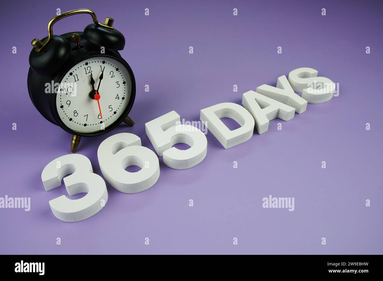 365 Days alphabet letters with alarm clock top view on purple ...