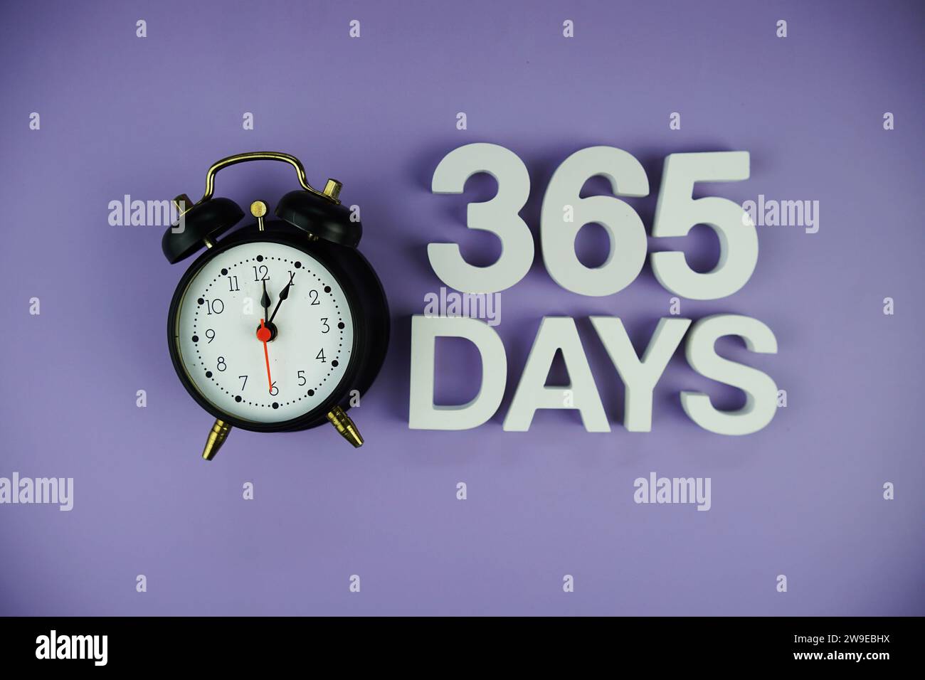 365 Days alphabet letters with alarm clock top view on purple ...