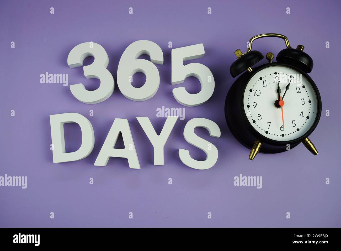 365 Days alphabet letters with alarm clock top view on purple ...