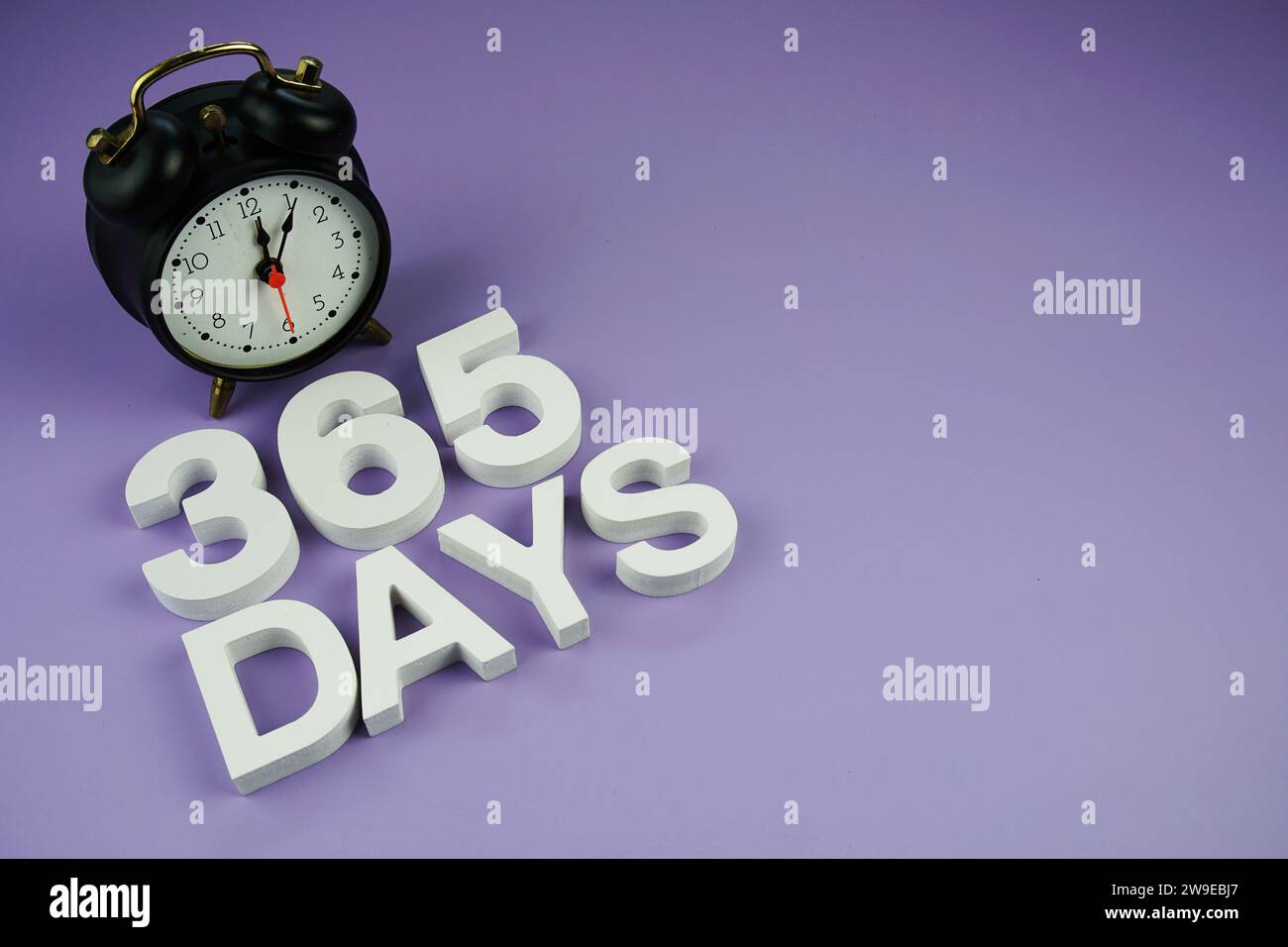 365 Days alphabet letters with alarm clock top view on purple ...