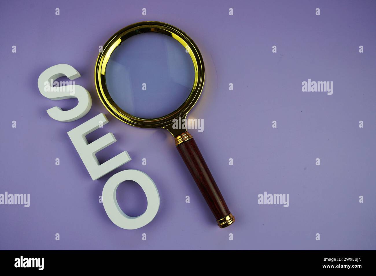 SEO letters and magnifying glass top view on purple background Stock ...