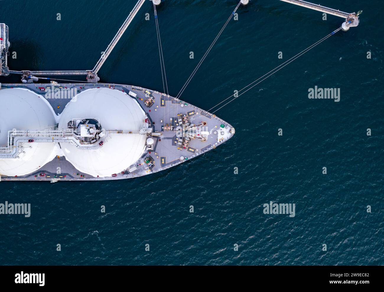Aerial top down of Liquified Natural Gas LNG carrier moored to a small ...