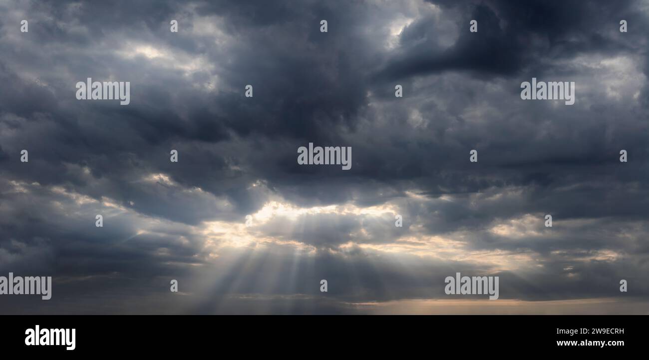 Sky background with sun rays shining through the dark rainy clouds ...