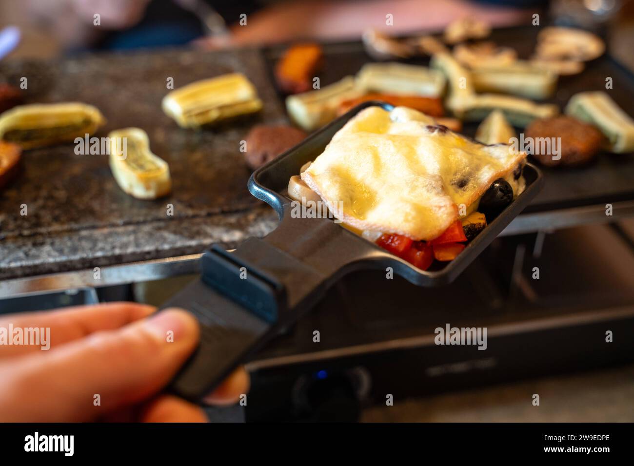 Bavaria, Germany - December 24, 2023: Man holding a raclette pan on a ...