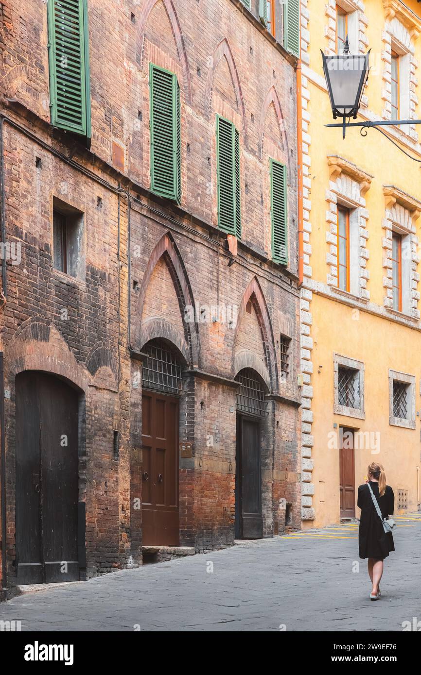 A young blonde female tourist explores a colourful quaint and narrow ...