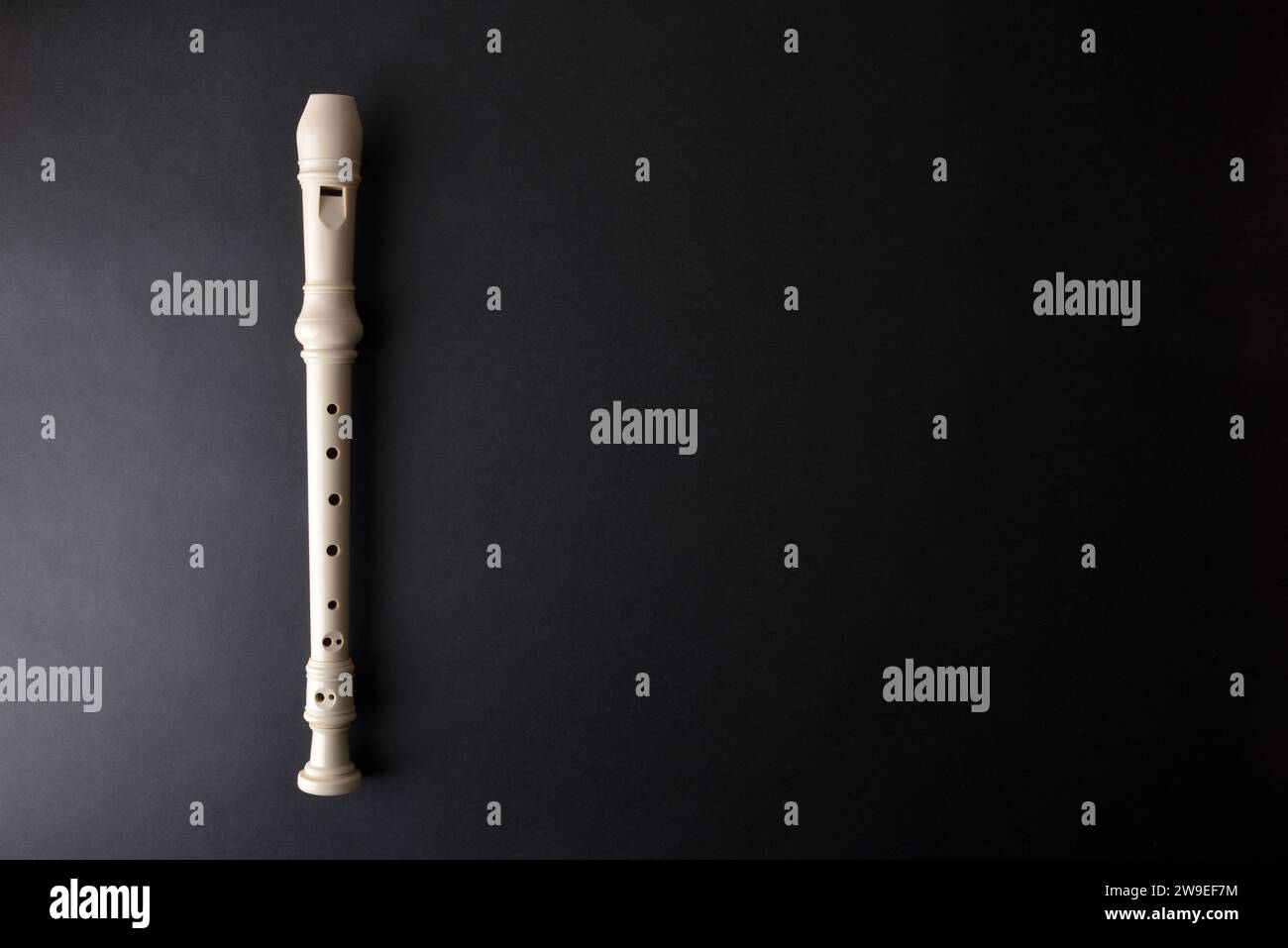Musical background with overview of white plastic recorder on black ...