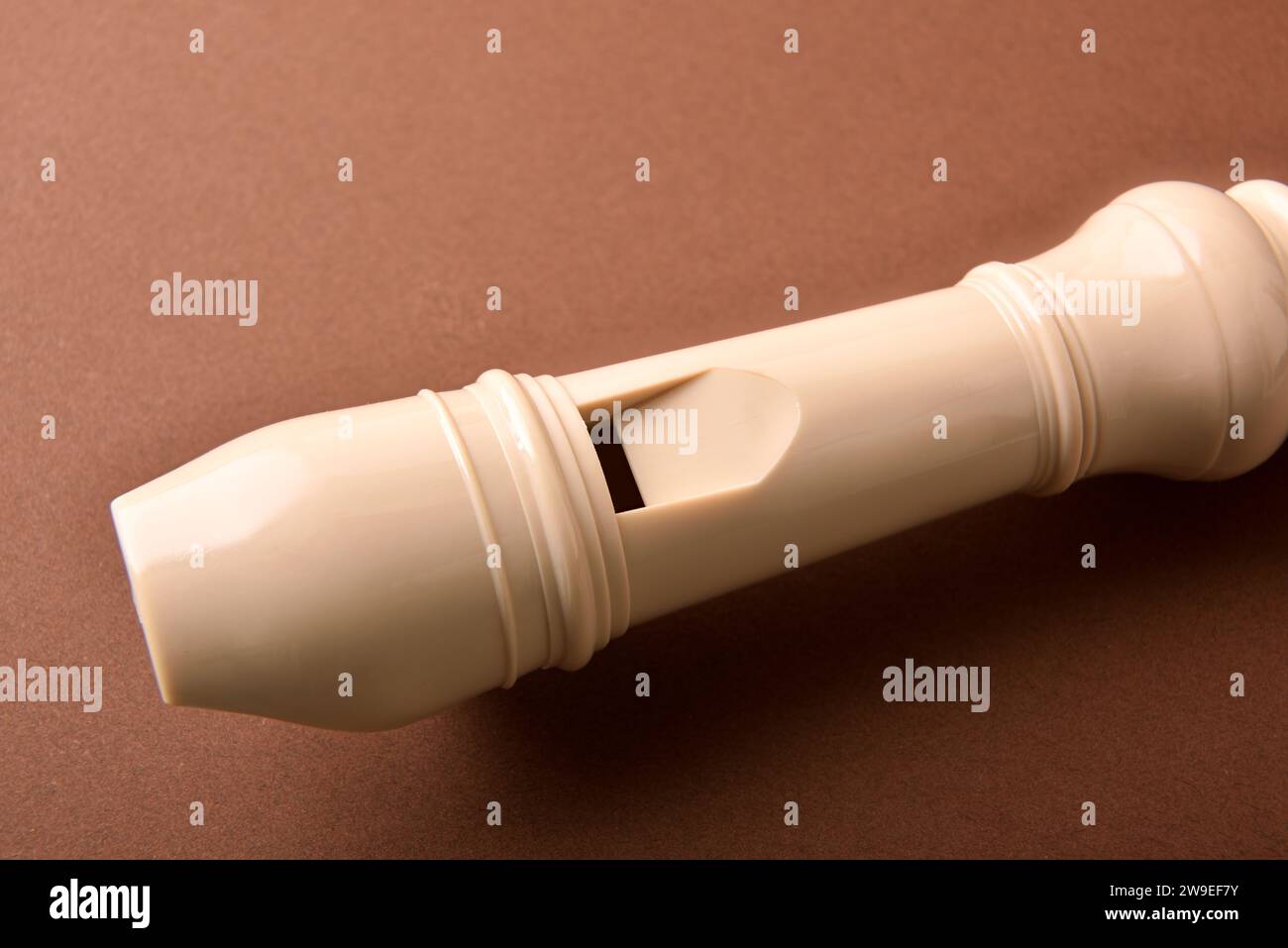 Detail of the mouthpiece of a recorder on brown table. Elevated view ...