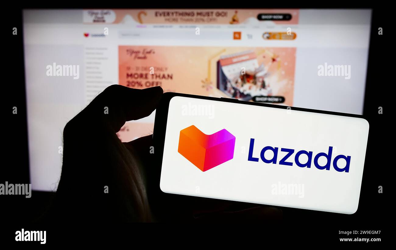 Person holding mobile phone with logo of Asian e-commerce company Lazada Group in front of ...