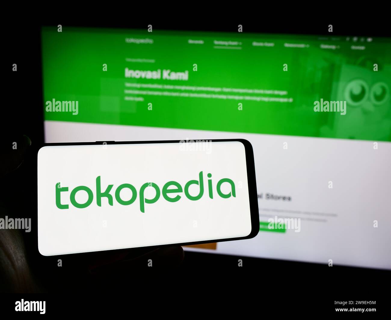 Person holding mobile phone with logo of Indonesian e-commerce company ...