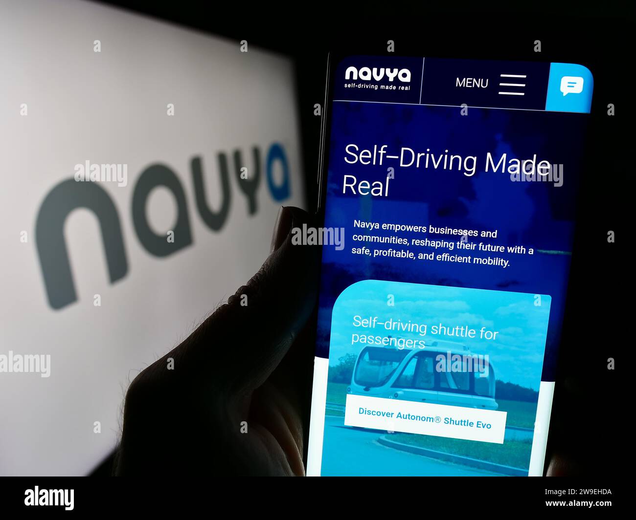 Person holding smartphone with webpage of French autonomous vehicle ...