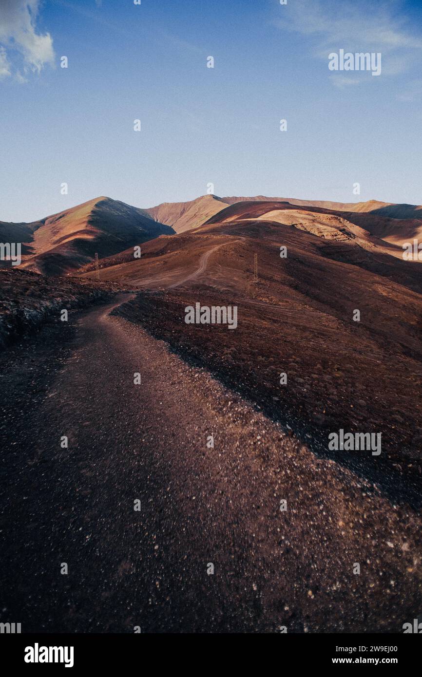 An empty hiking trail towards a mountain range Stock Photo - Alamy