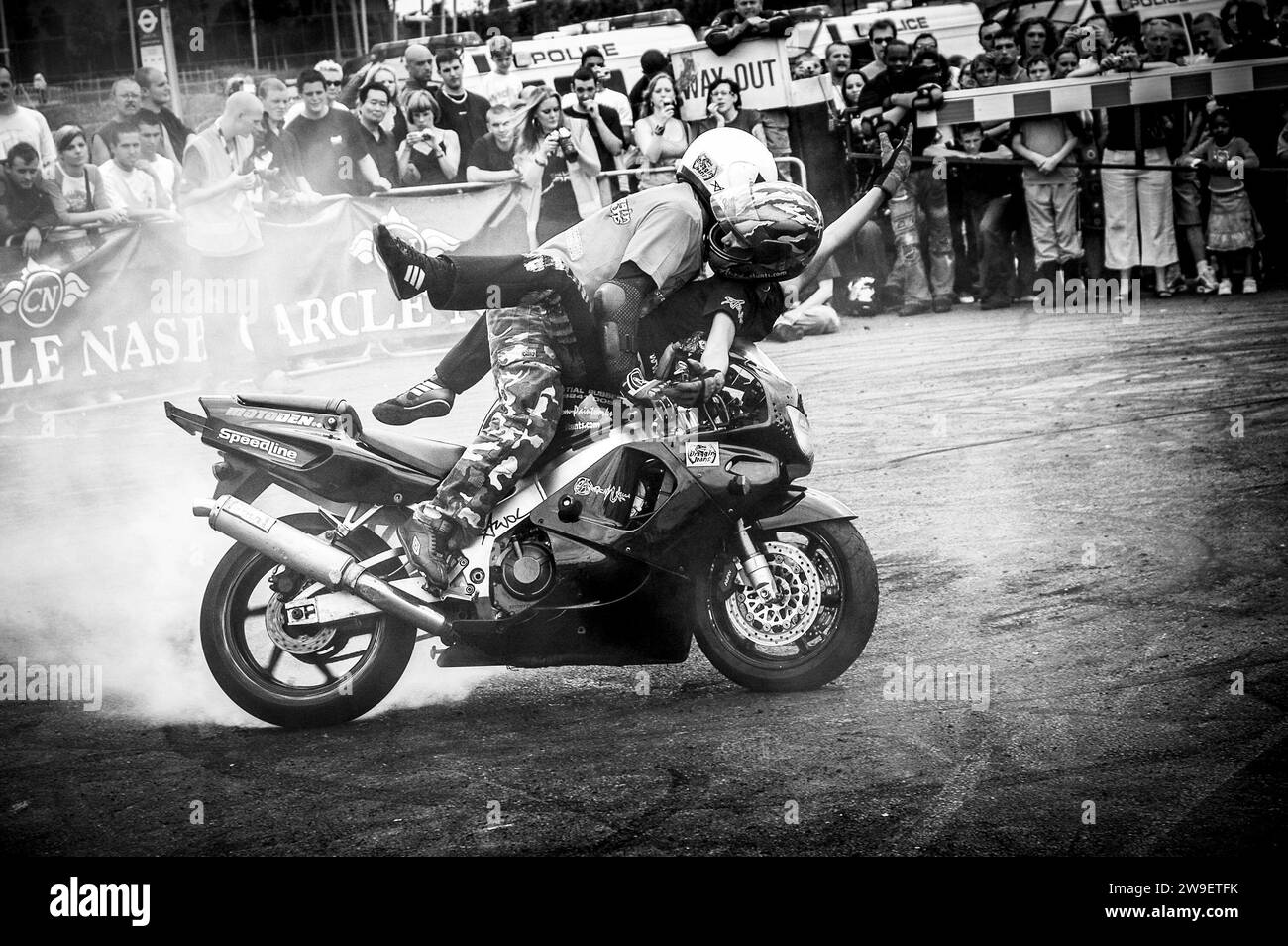 A stunt motorcyclist puts on a show for a crowd of people at a bike meeting in North West London ...