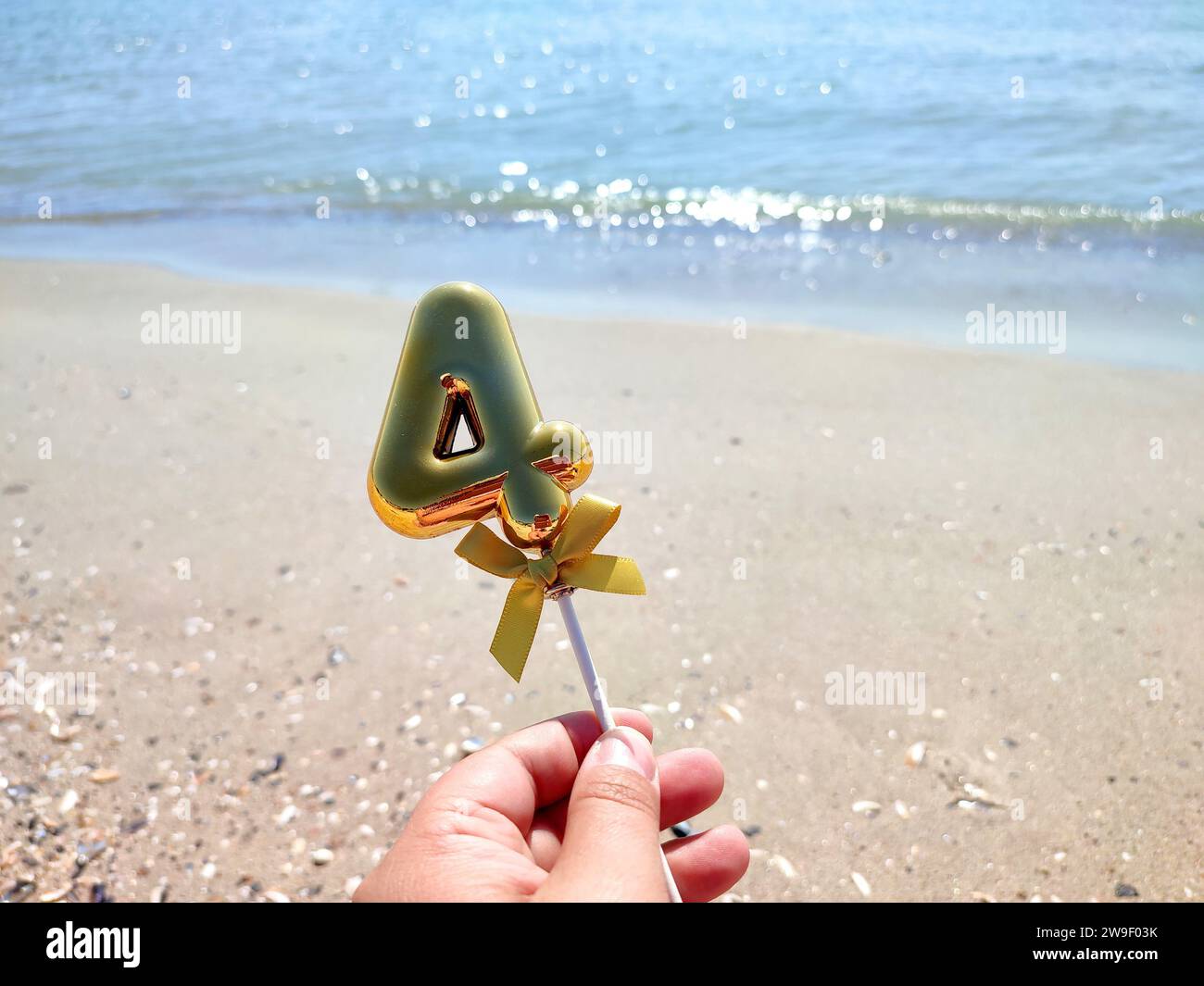 Person holding stick with a shiny golden number 4 four in his hand ...