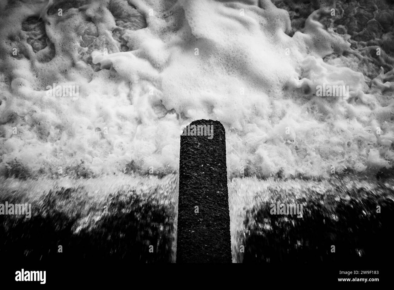 Water flows over a dam structure and crashes to the bottom of the ...