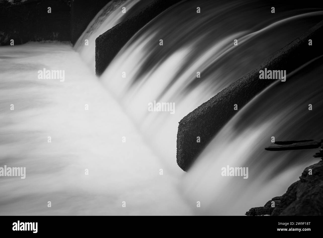 Water flows over a dam structure and crashes to the bottom of the ...