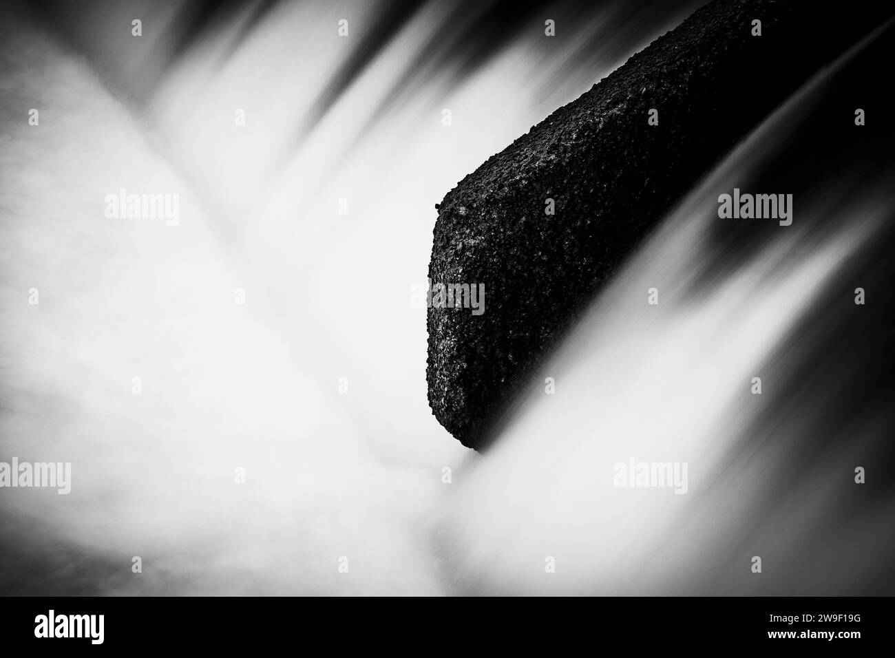 Water flows over a dam structure and crashes to the bottom of the ...