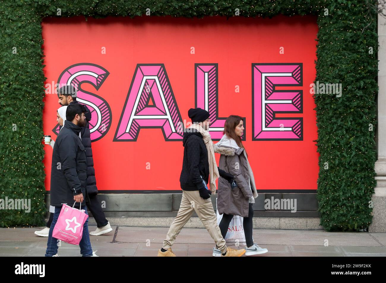 Shoppers walk past a sale sign in Selfridges on London's Oxford Street ...