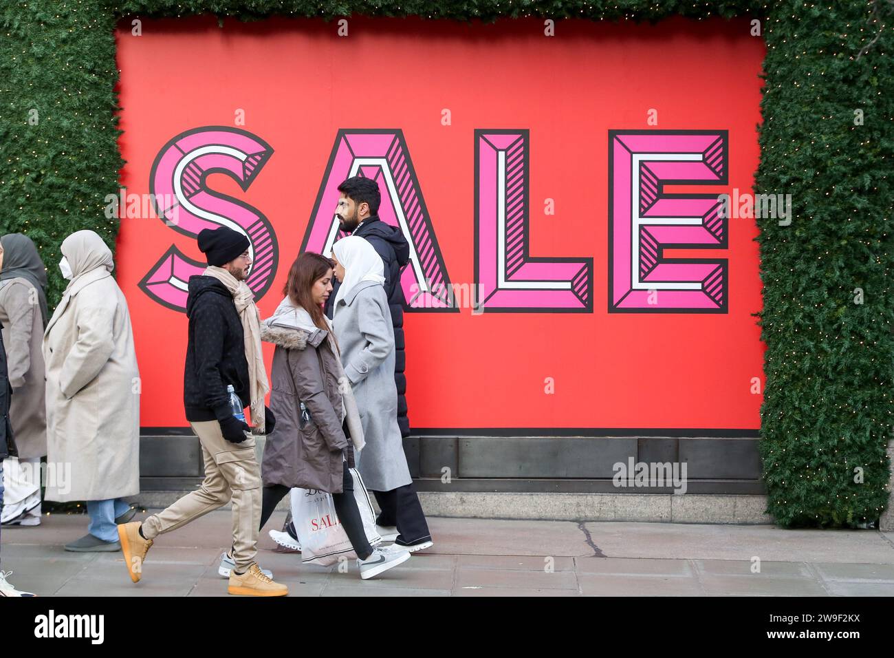Shoppers walk past a sale sign in Selfridges on London's Oxford Street ...