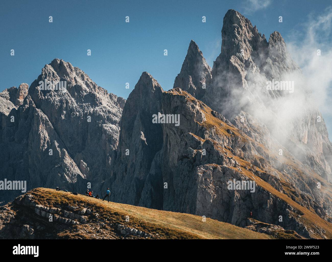 A diverse group of people walking single file along a winding mountain ...