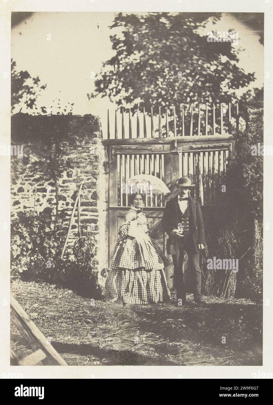 Portrait of an unknown man and woman with umbrella, standing in front ...