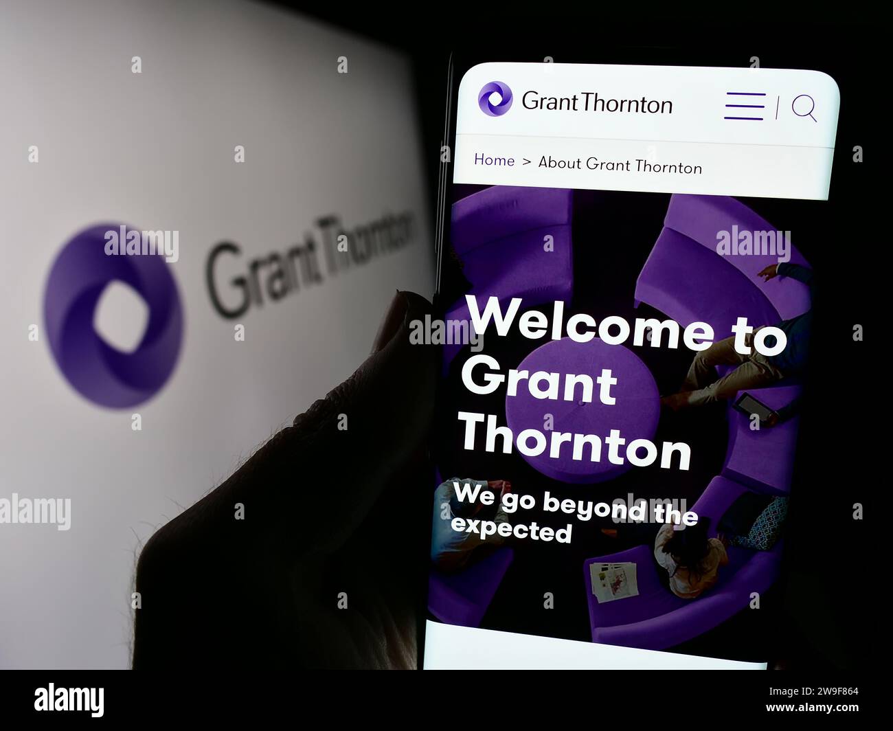 Person holding cellphone with website of consulting company Grant ...