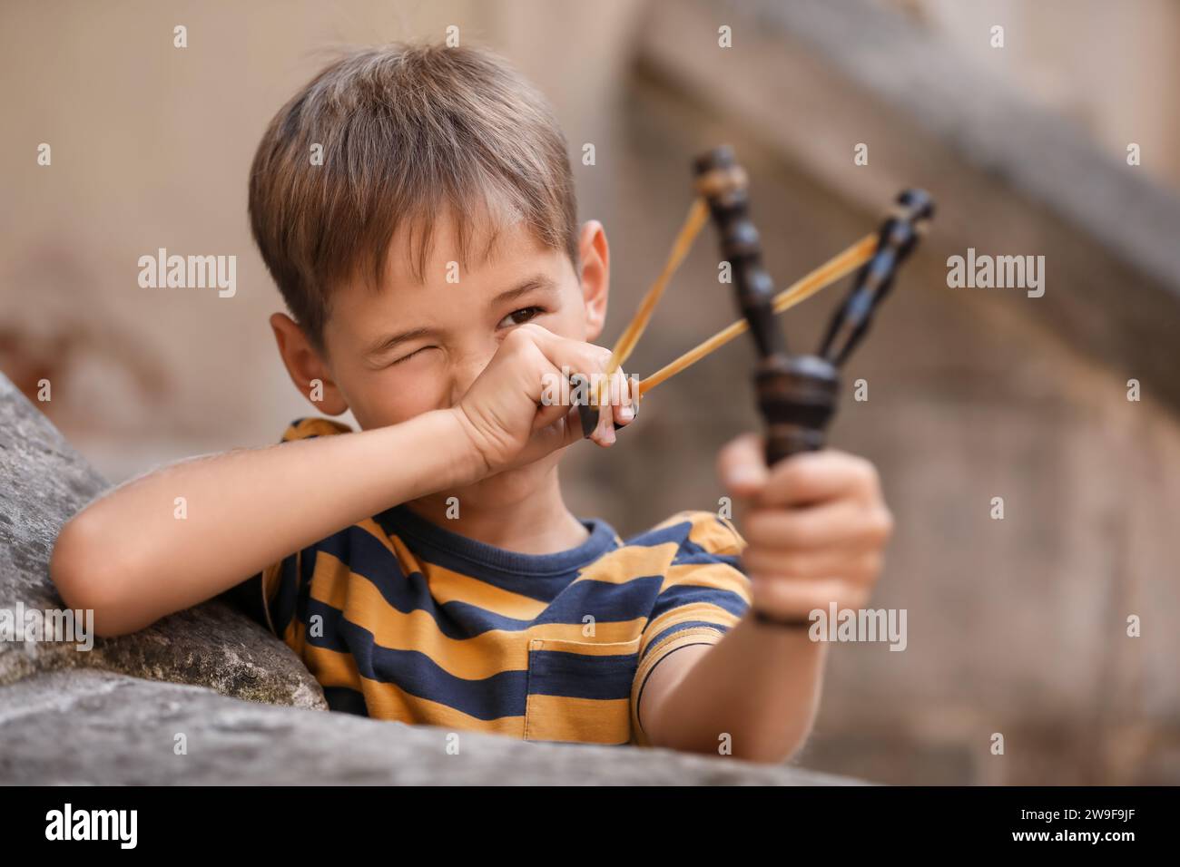 Cute little boy playing with slingshot outdoors Stock Photo - Alamy