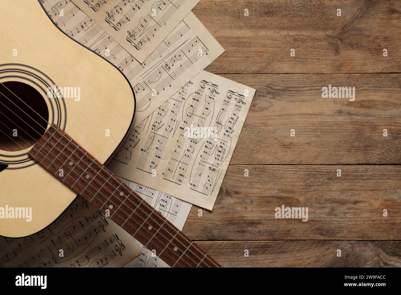 Paper sheets with music notes and acoustic guitar on wooden table, top ...