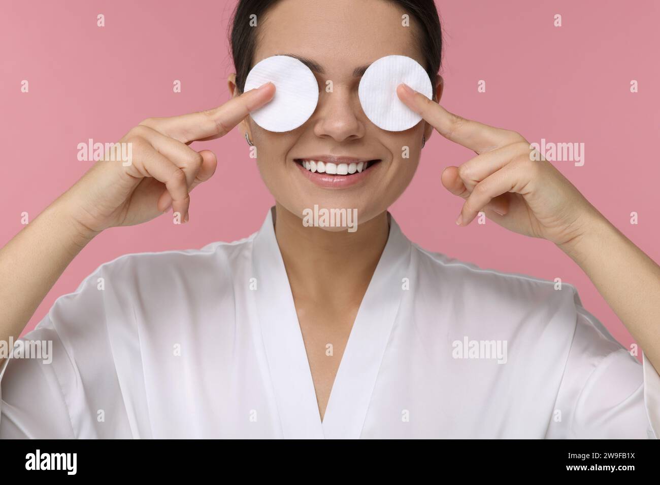 Young woman covering her eyes with cotton pads on pink background Stock ...