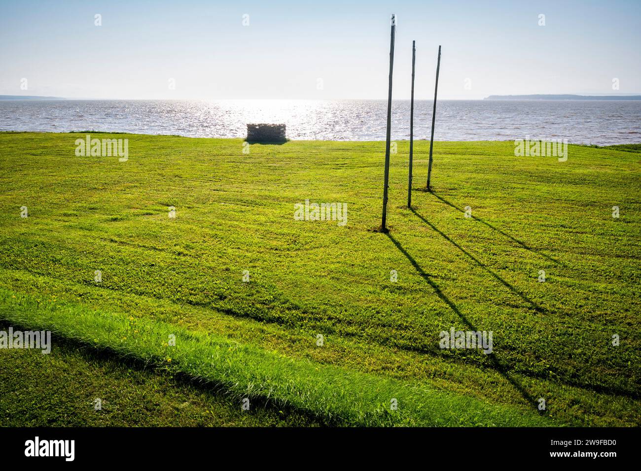 Three poles cast shadows along the Bay of Fundy shore in Joggins, Nova ...