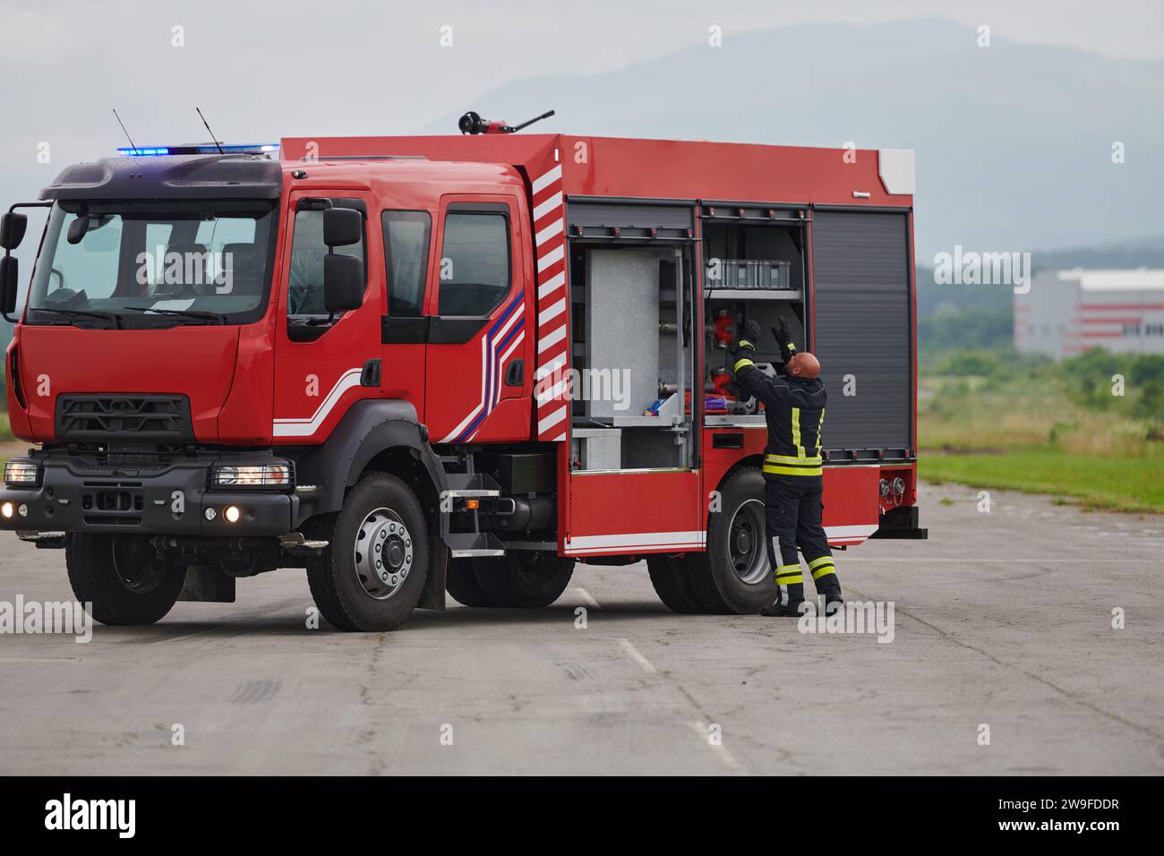A firefighter meticulously prepares a modern firetruck for a mission to ...