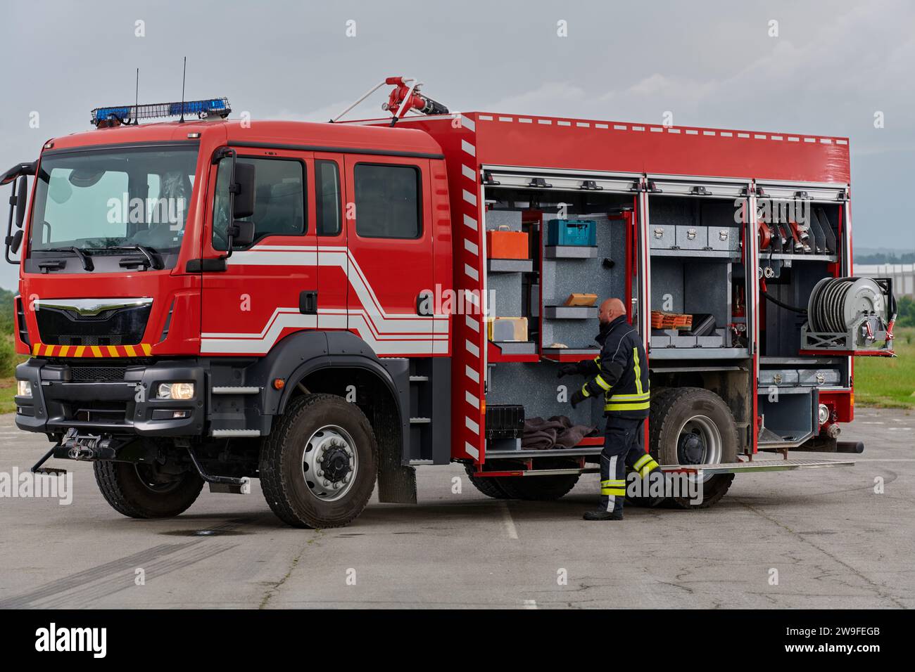 A firefighter meticulously prepares a modern firetruck for a mission to ...