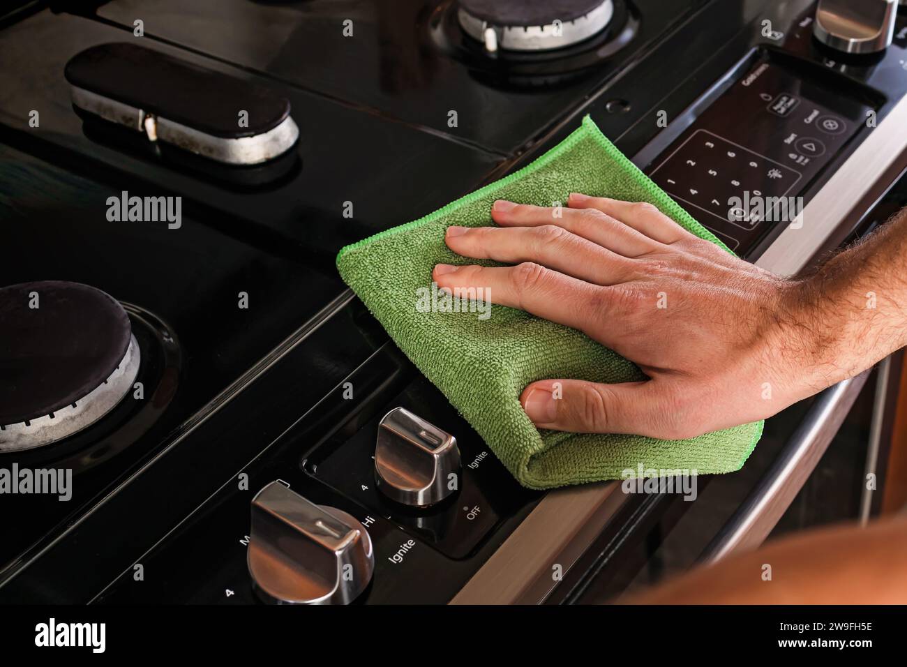Male hand wiping the stove with green colored cloth close-up, man ...
