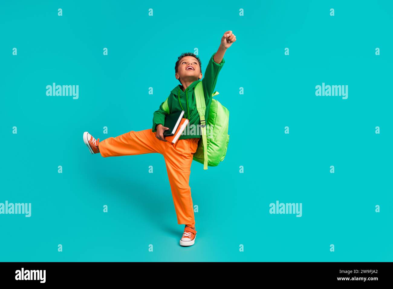 Full size photo of cheerful boy wear green hoodie hold book catching ...