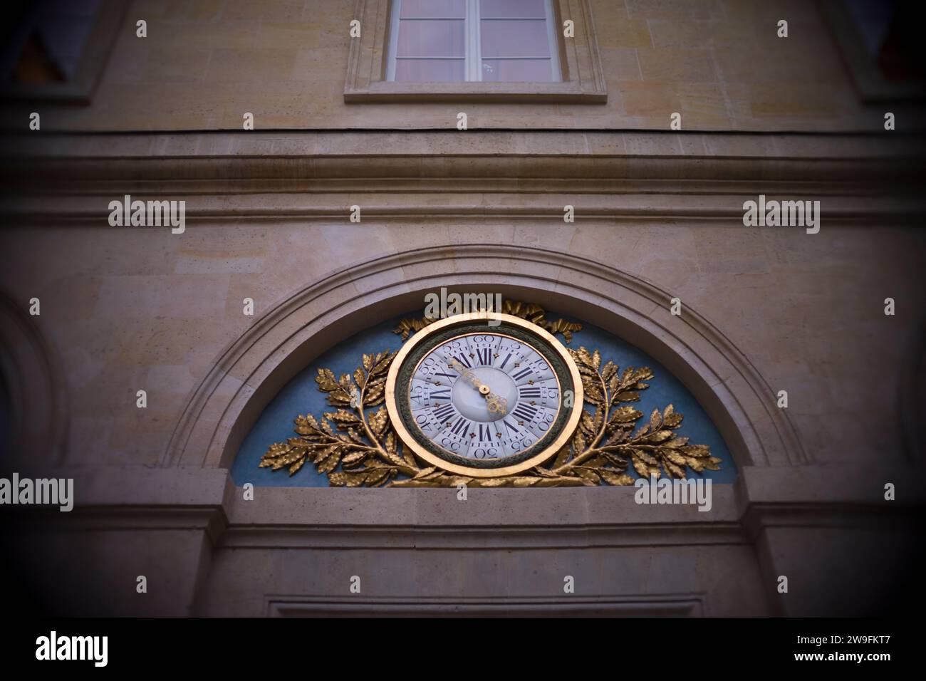 Elegant building facade with ornate clock and decorative golden laurel ...